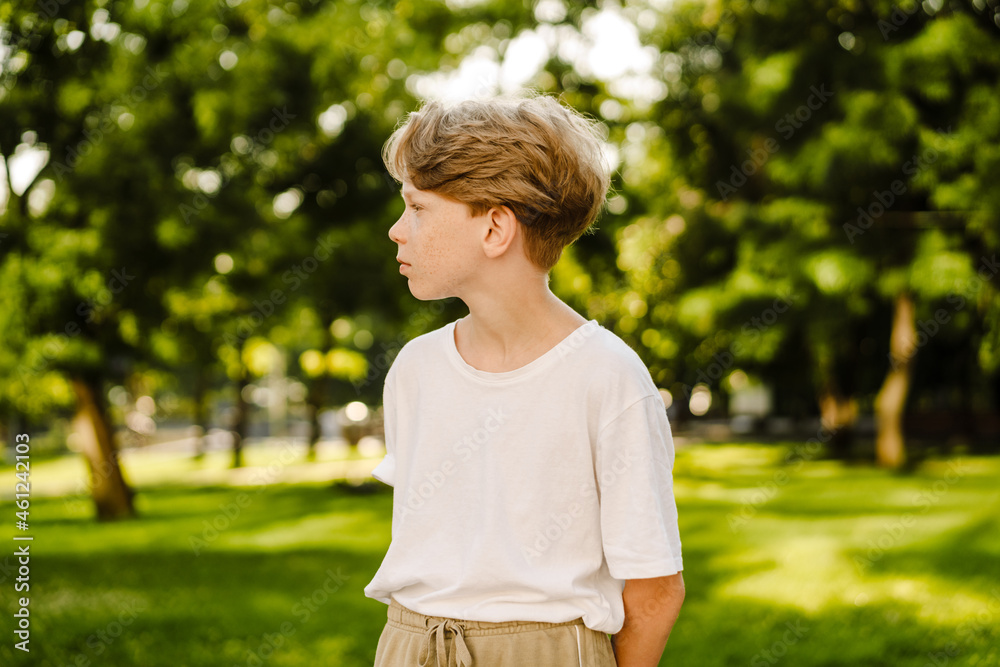 Ginger white boy looking aside while standing in green park Stock Photo ...
