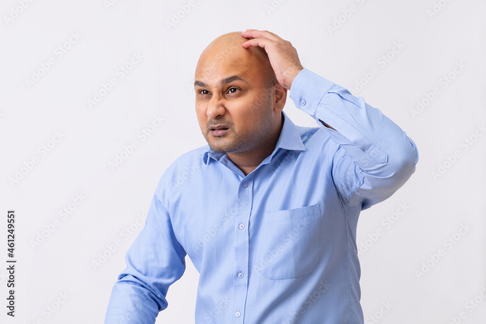 Portrait of a bald man wearing shirt scratching his shaved head against ...