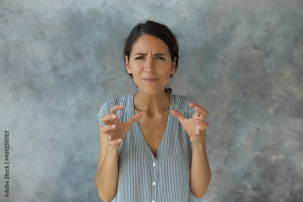 Studio shot of angry, displeased woman dressed casually holding hands ...
