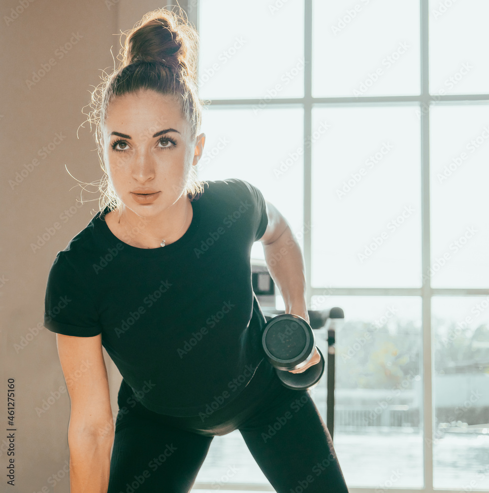 Strong muscular woman focus workout on pumps up the muscles by one arm ...