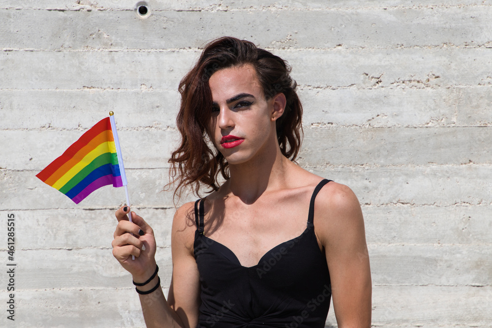 young latin and transsexual woman on grey background holding the gay ...