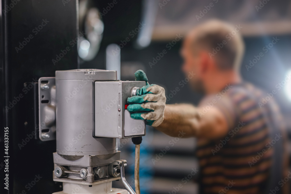 factory worker presses a button to stop the machine tool production ...