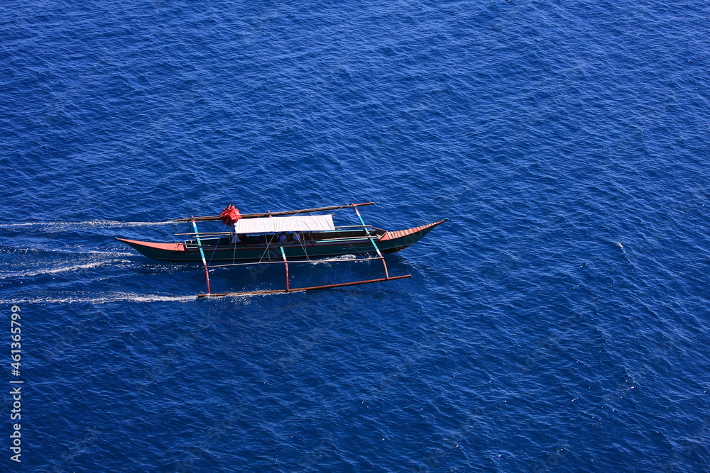 traditional Filipino bangka boat motoring through a clam ocean in the ...