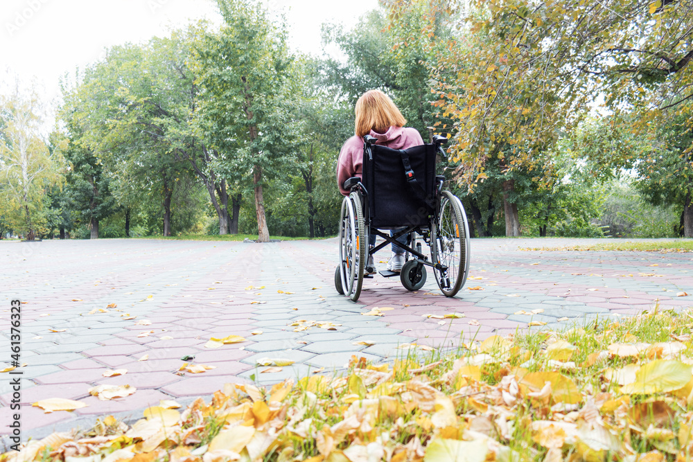 disabled teenage girl in a wheelchair from the back for a walk in the ...