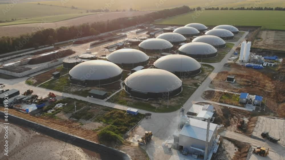 Biogas farm on green fields. Renewable energy from biomass. Modern agricultural biogas plant ...