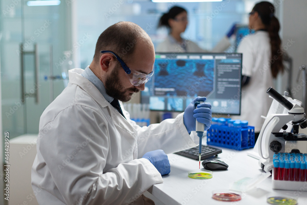 Scientist biologist man putting chemical fluid in petri dish using ...