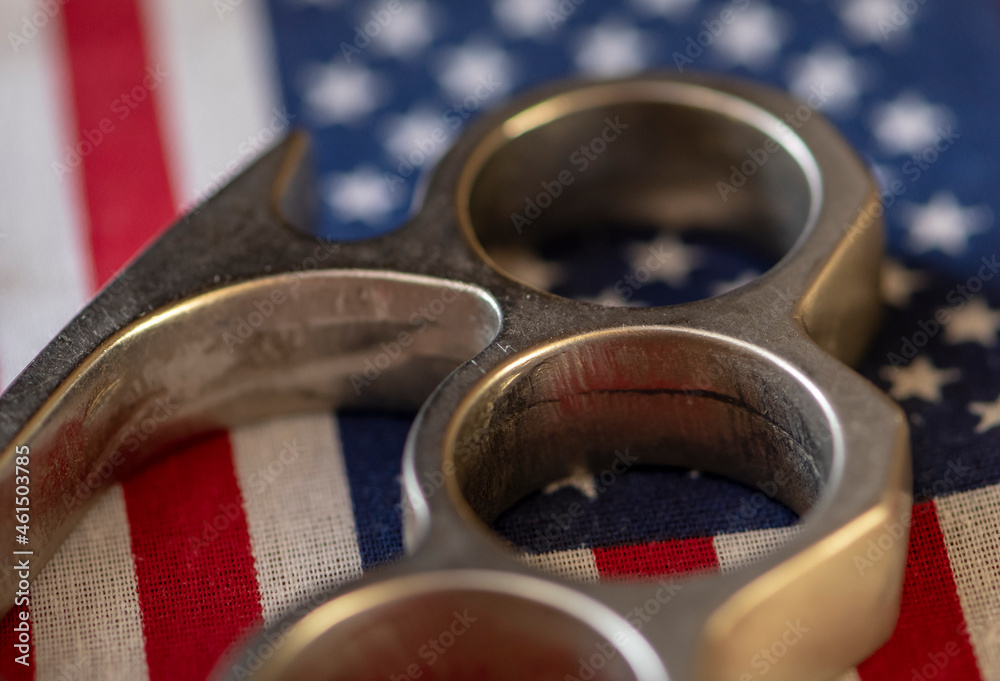 Metal brass knuckles lying on the background of the American flag ...