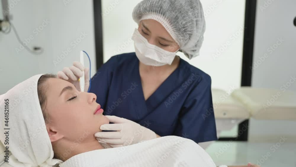 Beautiful Asian woman lying on bed and professional cosmetologist ...