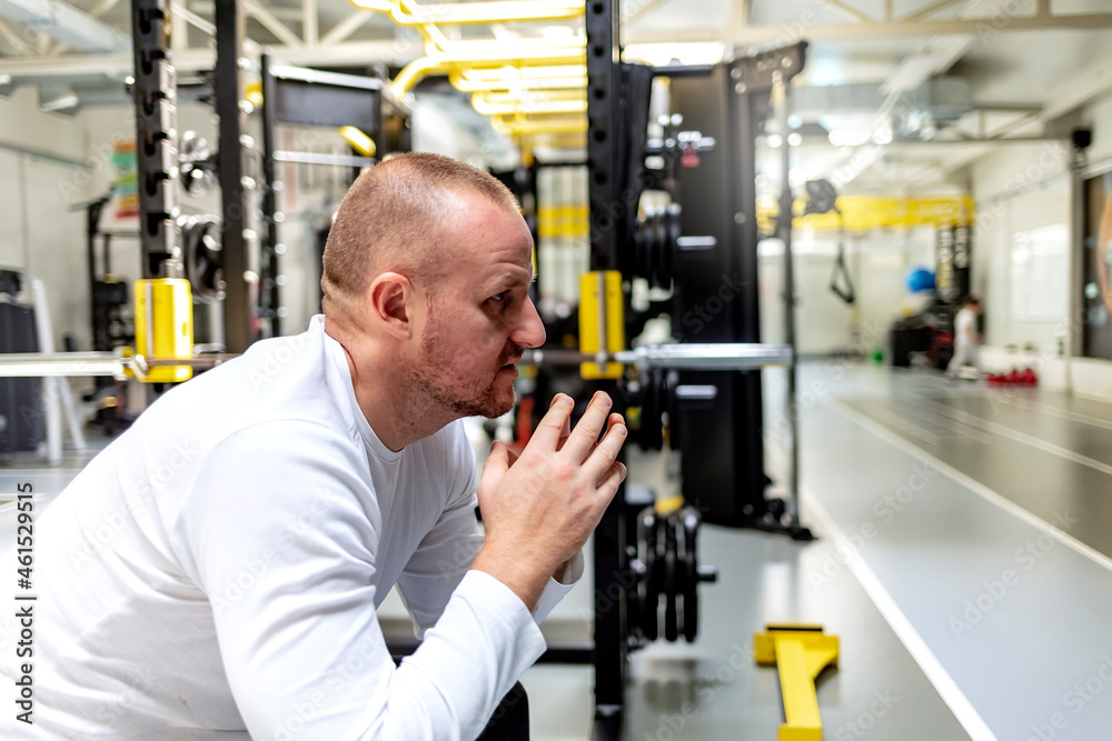 Handsome young muscular man resting in gym while looking away. Portrait ...