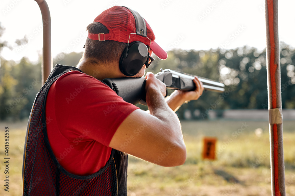 Side view on caucasian Man in cap and headset shooting at target on an ...