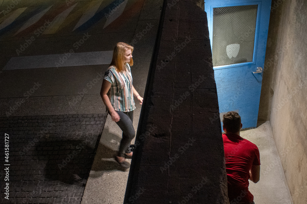 Young woman walking outside at night towards stairwell with male ...