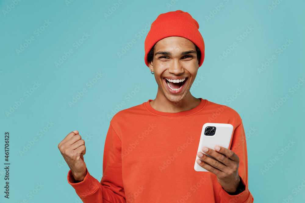 Young overjoyed fun happy african american man in orange shirt hat use ...