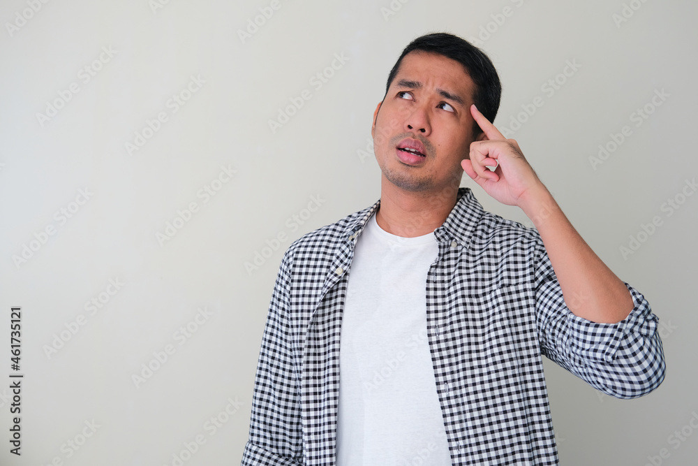 Adult Asian man pointing finger to his head and showing thinking ...