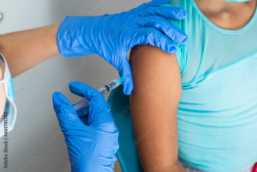 children's nurse injecting arm of brown girl. doctor injecting covid-19 ...