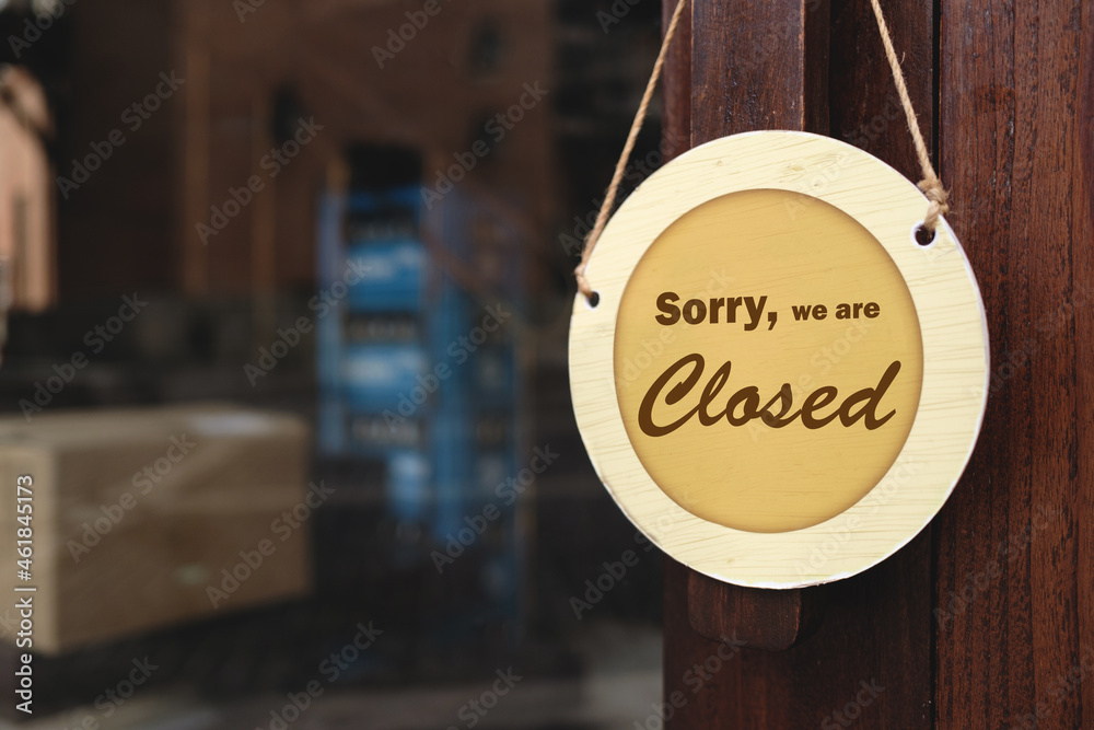 Sign hanging outside a restaurant, store, office with text sorry we're ...