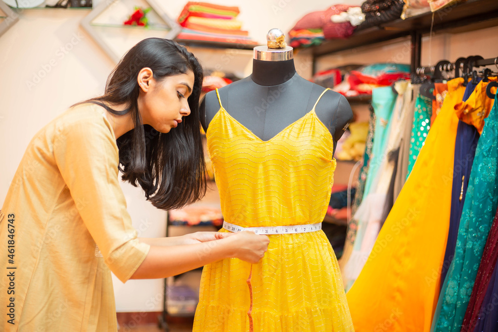 Young indian woman tailor or dressmaker checking measurements on ...