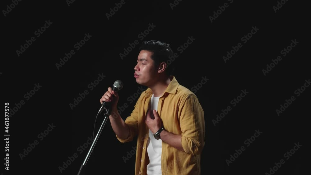 Side View Of Asian Man Singer Singing Into Microphone On Black ...