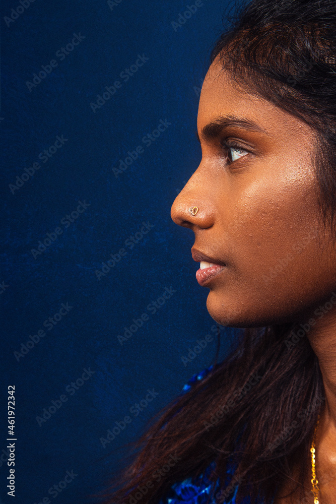 portrait of dark skinned Indian woman from Malaysia against dark blue ...