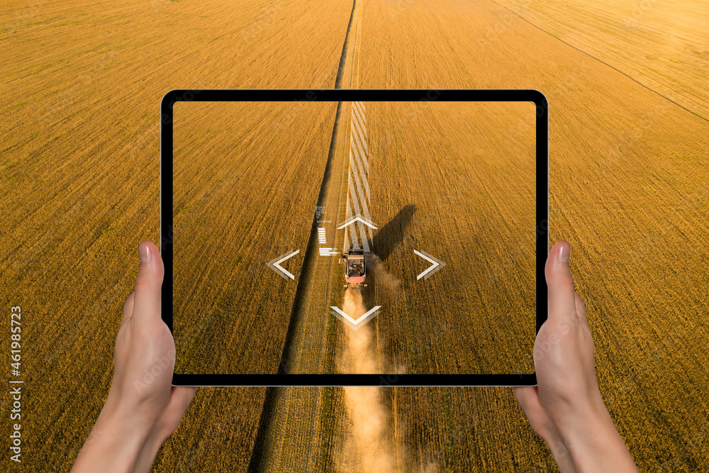 Farmer with digital tablet controls an autonomous harvester. Smart ...