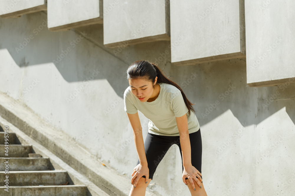 Tired asian woman with ponytail in stylish tracksuit bends leaning on ...