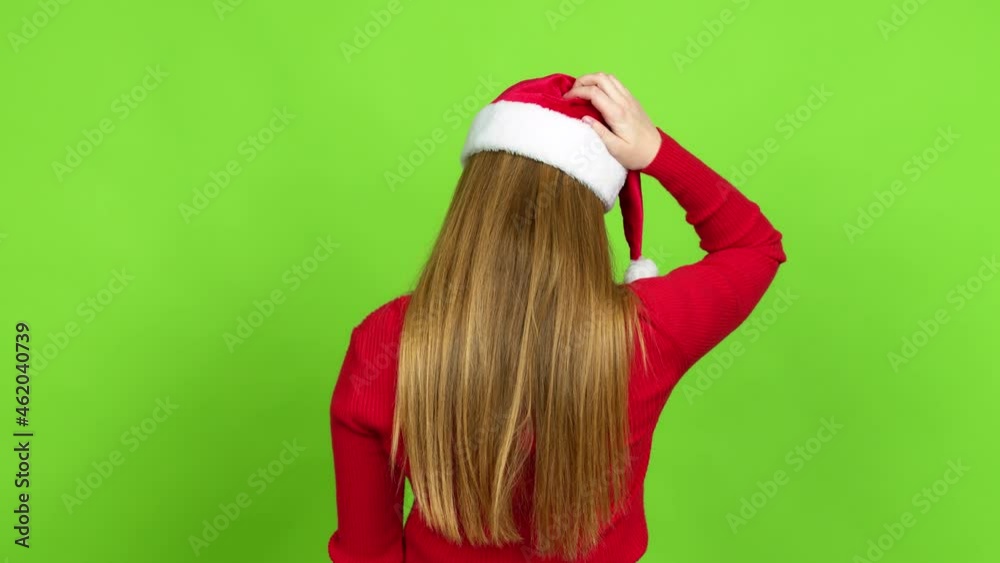 Teenager girl with christmas hat on back position looking back while ...