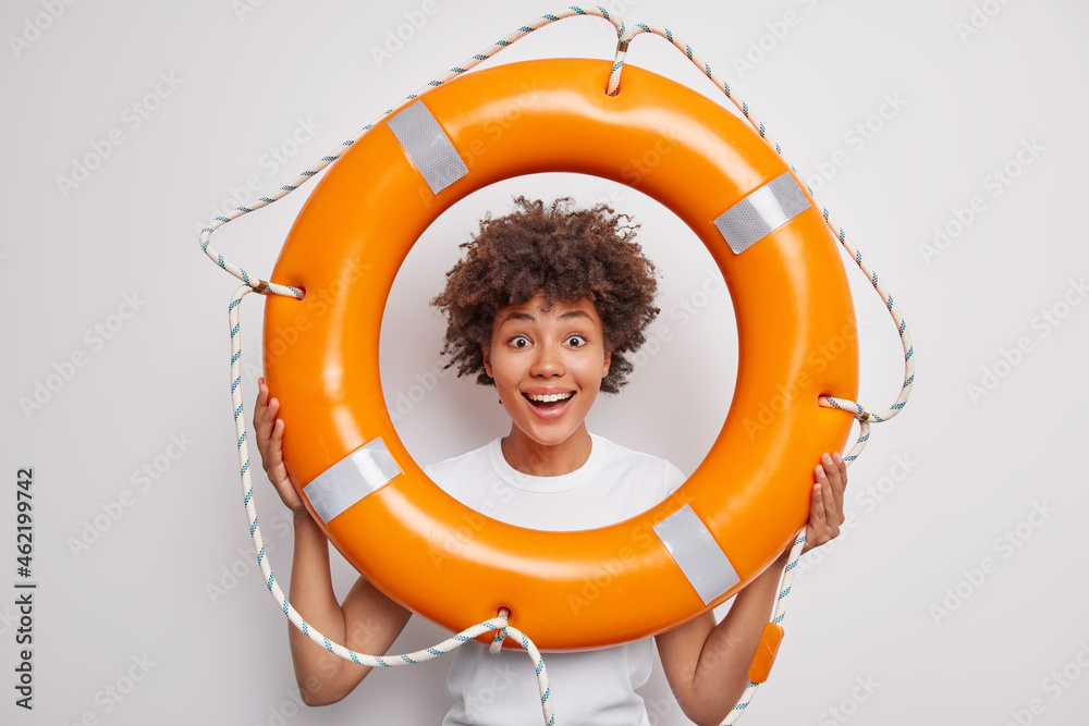 Positive ethnic female looks through lifesaver smiles broadly ready for ...