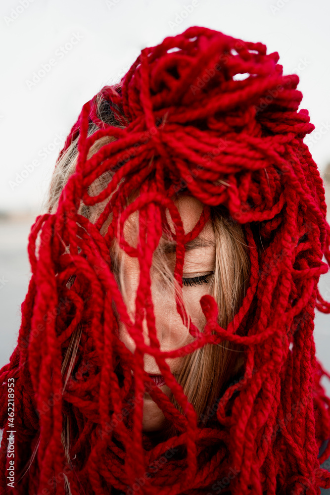 Woman covering face with red thread Photos | Adobe Stock
