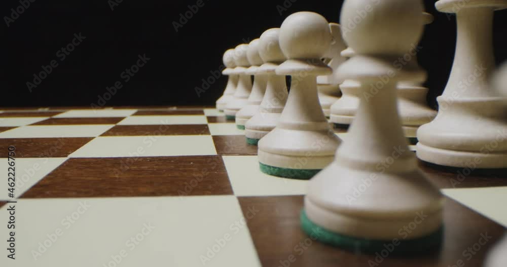 White chess pieces are lined up in even rows on a game board, ready for ...