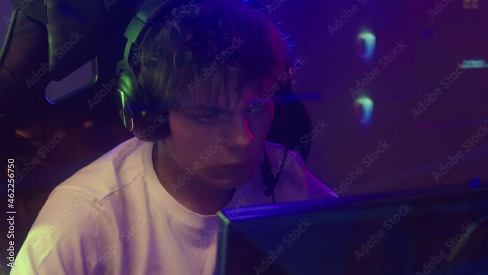 A young gamer is intensely staring at the computer monitor. A young ...