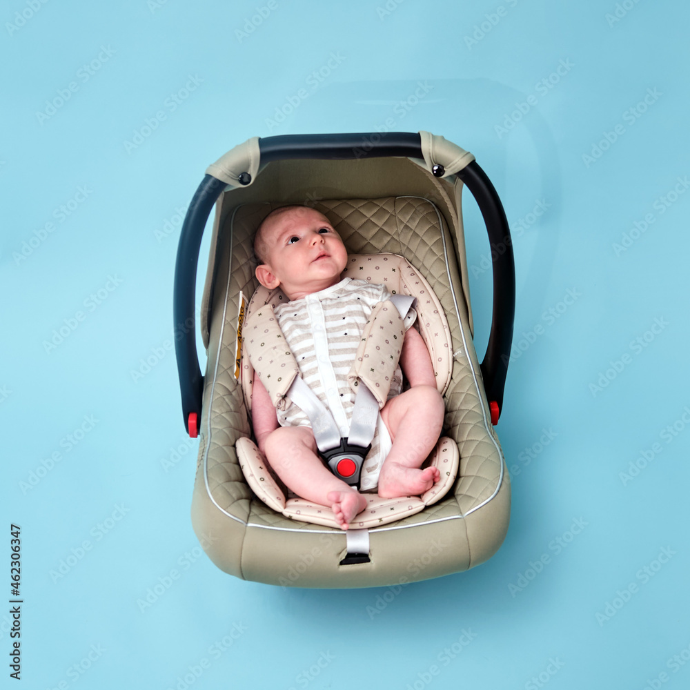 Baby in infant car seat on blue studio background. Carrier for ...