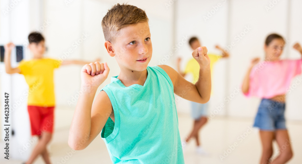 Portrait of cheerful preteen boy learning energetic dance moves with ...