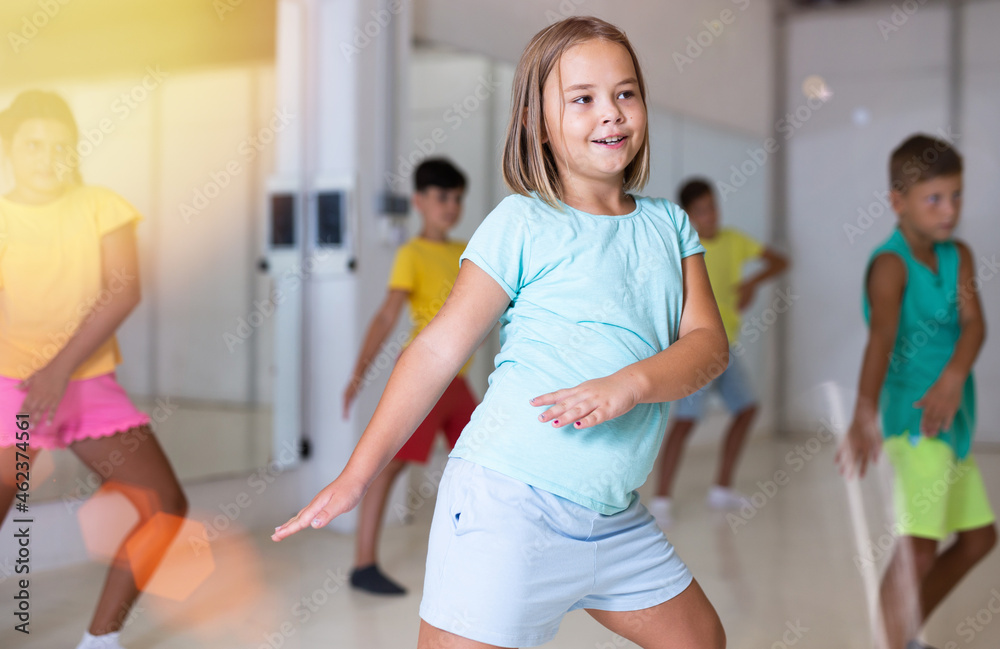 Portrait of cheerful preteen girl learning energetic dance moves with ...
