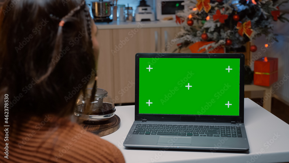 Caucasian woman looking at green screen on laptop while sitting in ...