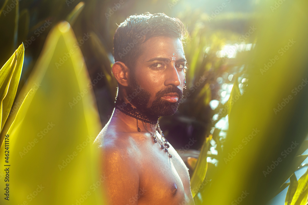 portrait of a dark skinned Indian man by a lake, shirtless, with make ...