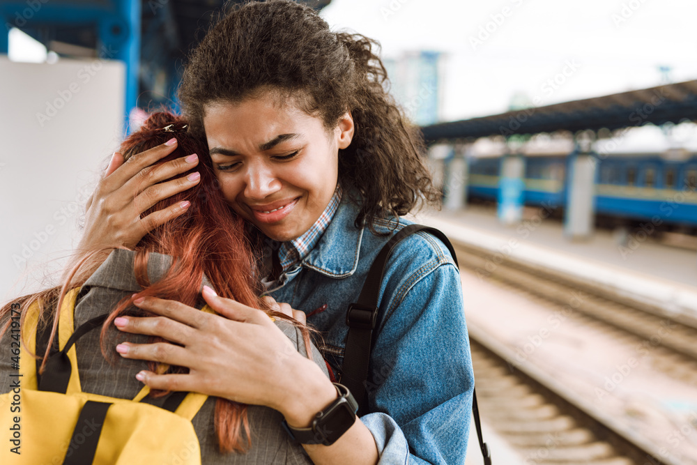 Multiracial two women hugging while saying goodbye at train station ...