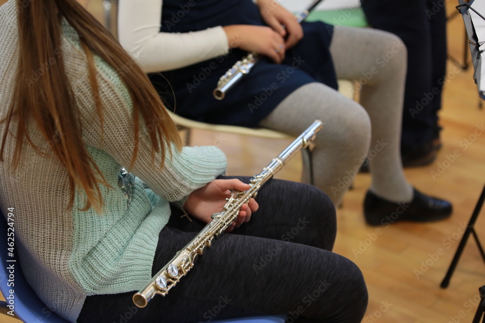 Girl student with a musical instrument flute sitting in the hall at the ...