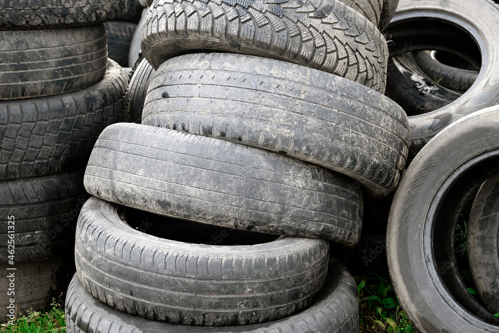 Pile of old dirty worn-out rubber tire tires on the grass. Concept of ...