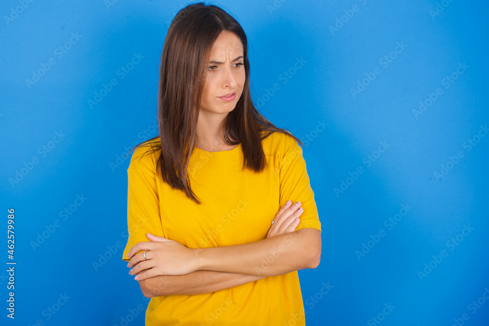 Displeased Young european brunette woman wearing yellow T-shirt on blue ...
