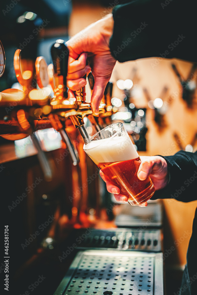 bartender hand at beer tap pouring a draught beer in glass serving in a bar or pub Stock Photo ...