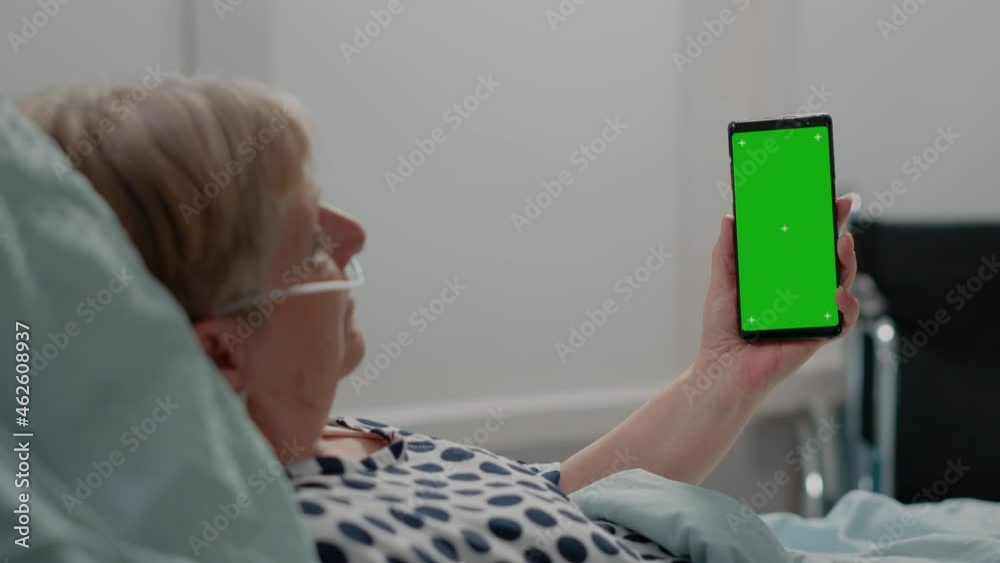 Close up of ill patient vertically holding green screen on smartphone ...