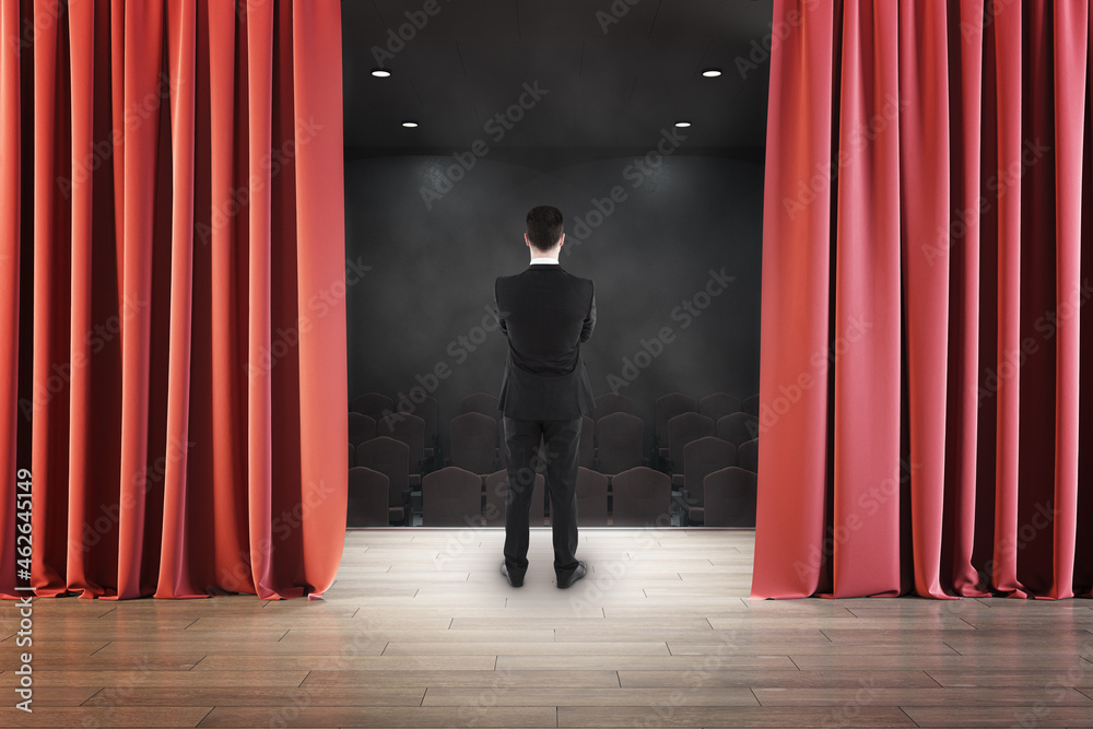 Back view of businessman looking at stage from behind red curtain ...