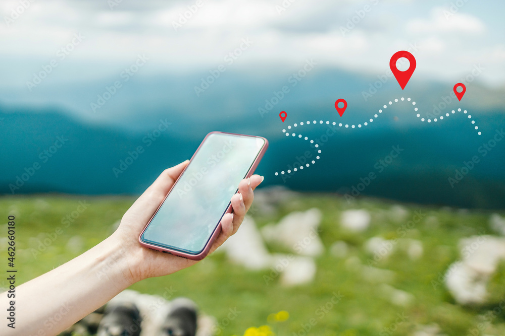 Woman hand using smart phone on top of mountain with navigator location ...