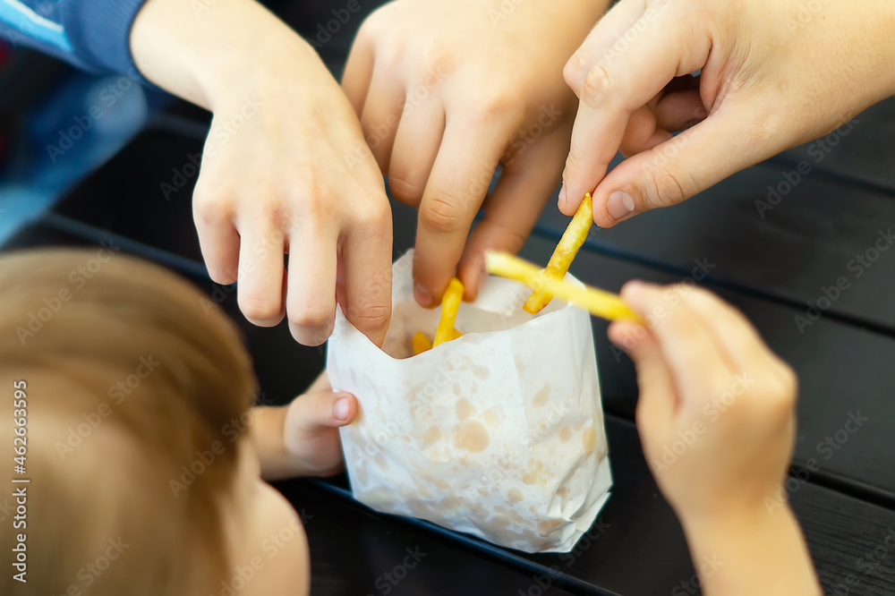 Teenagers take French fries from their younger sister. The family is ...