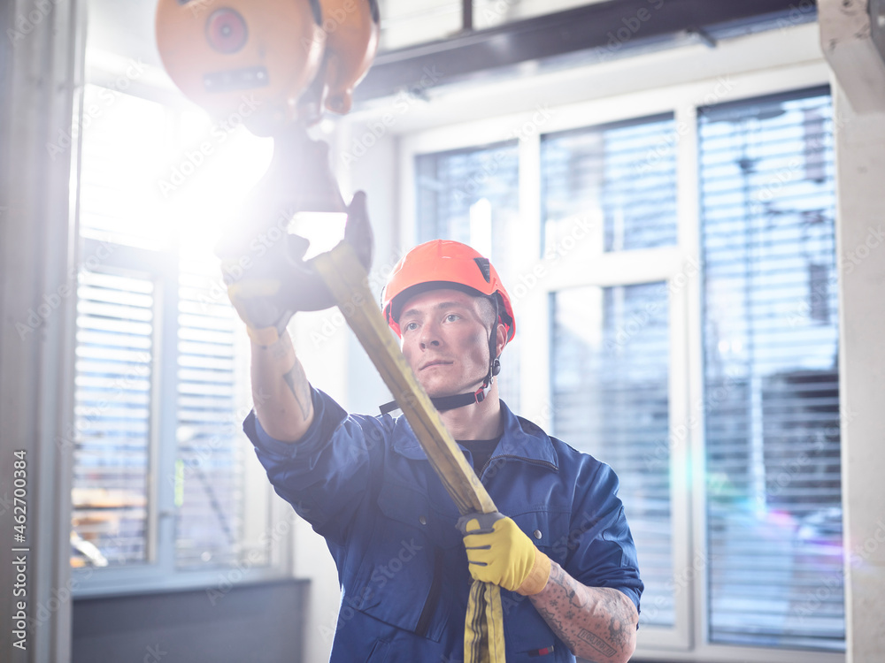 Industrial worker fixing hoist sling on indoor crane Stock Photo ...