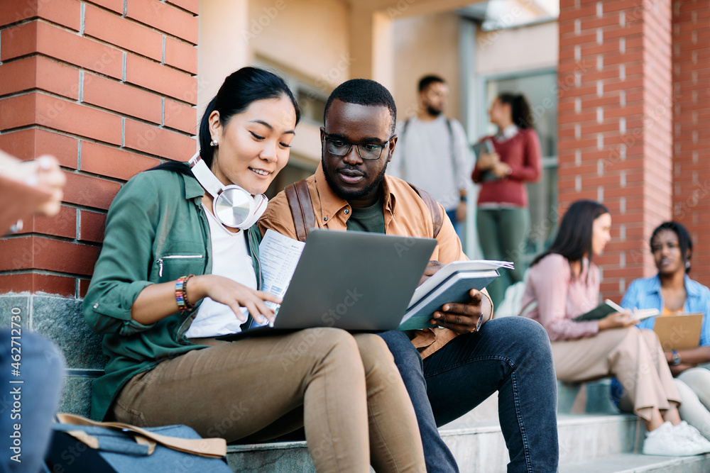 Young multiracial students use laptop while learning at campus. Stock ...