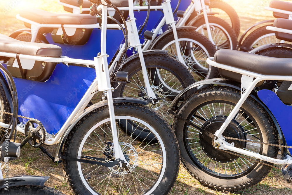 Many retro fat electric bicycle scooters parked on dirt grass field ...