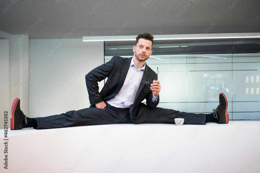 Businessman doing the splits on reception desk in office Stock Photo ...