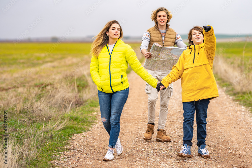 Three siblings hiking with map along dirt road Stock Photo | Adobe Stock