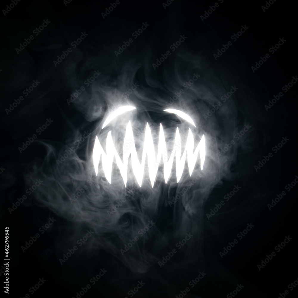 Horror face glows in darkness through thick smoke clouds creating ...