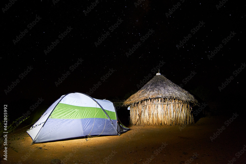 Ethiopia, Turmi, Tent pitched next to traditional African hut at night ...
